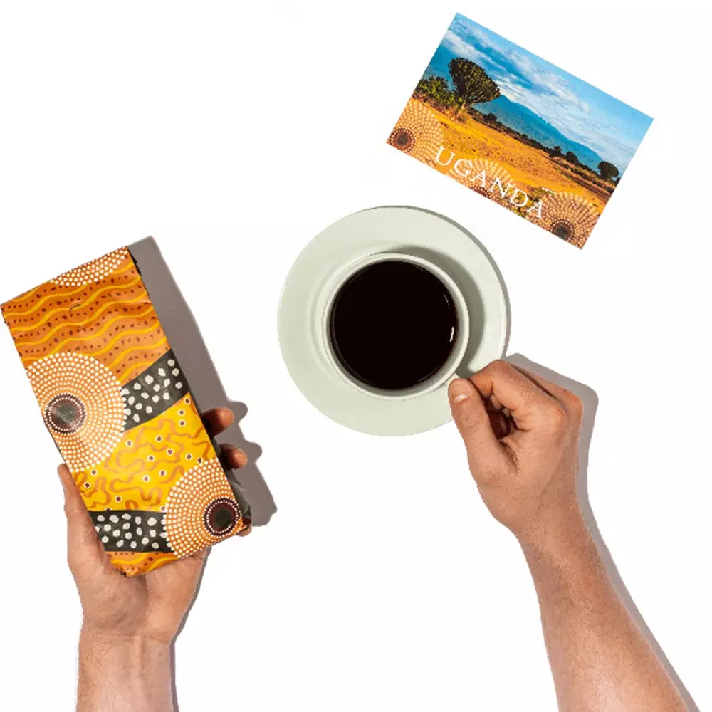 Leungeunna nyekelan kantong kopi jeung mug jeung kartu pos